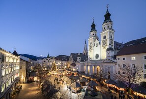 Uma praça histórica com arquitetura tradicional, incluindo uma igreja de destaque com duas torres e uma área de mercado.