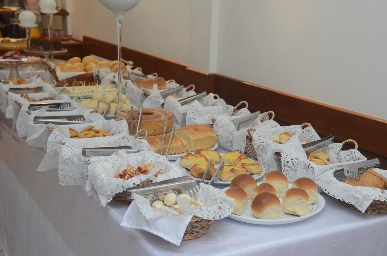 Uma mesa de buffet com diversos alimentos, incluindo pão, doces e pães, dispostos em cestos e pratos.