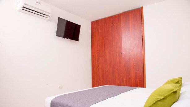 Quarto com cama, guarda-roupa, televisão e aparelho de ar condicionado.