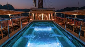 Área da piscina com espaço de estar coberto e vista para a água.