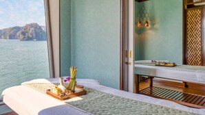 Um quarto com uma cama, um bandejão com produtos de higiene e vista para o mar.