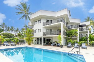 Um hotel moderno com piscina, várias varandas e paisagismo tropical.