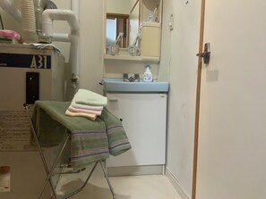 Um banheiro pequeno com pia, espelho e porta-toalhas com toalhas dobradas.