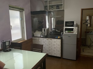 Uma cozinha compacta com geladeira, micro-ondas, pia e uma janela com persianas.