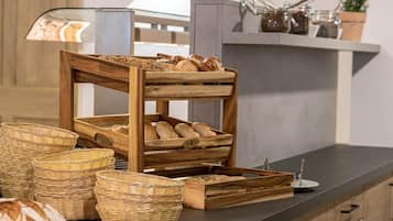 Suporte de madeira para pão com diferentes pães e cestos em uma bancada de cozinha.