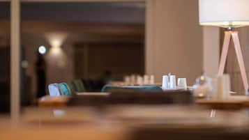 Visão desfocada de um quarto de hotel com sofá, luminária e uma mesa com chávenas e garrafa.
