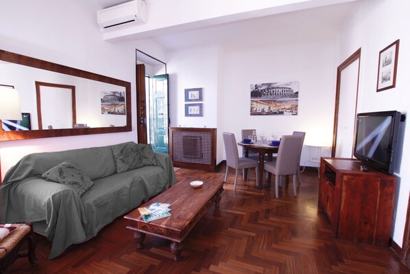 Sala de estar com sofá, mesa de centro, televisão e área de jantar.