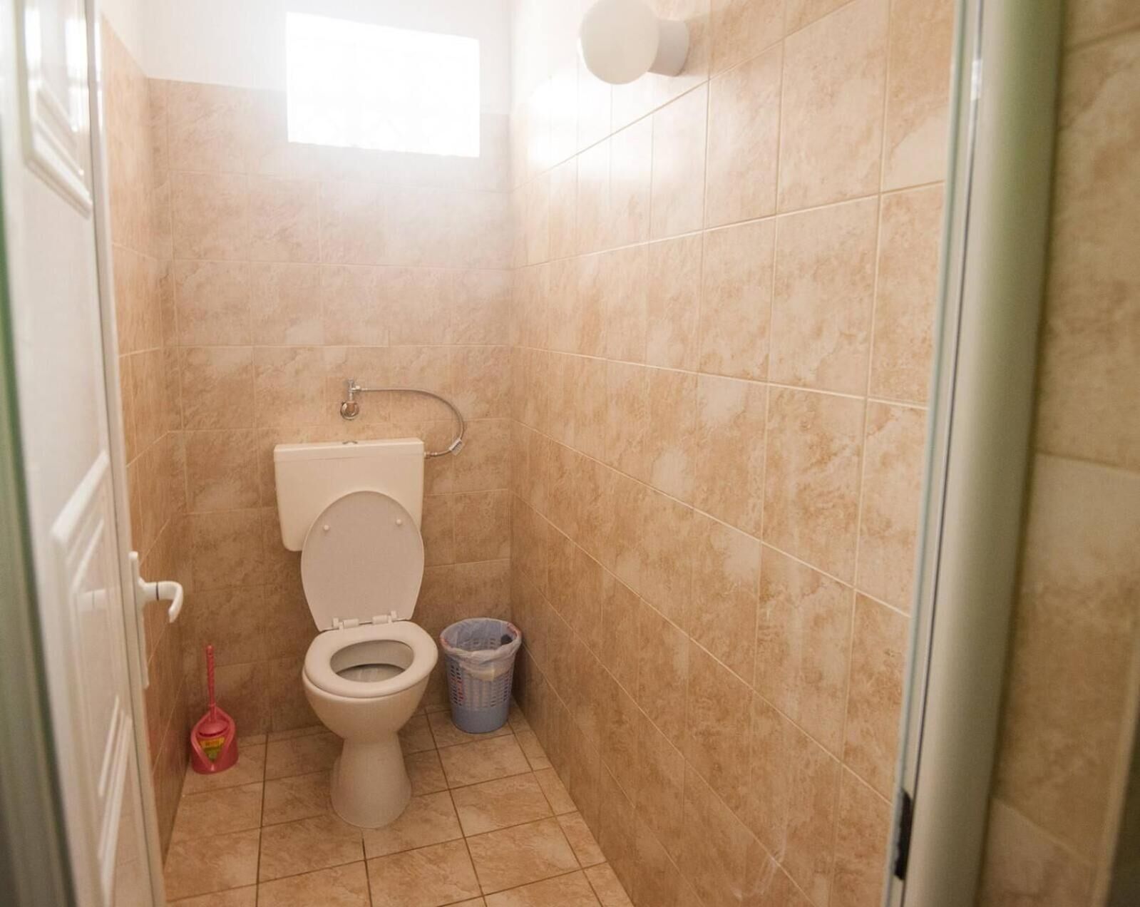 Casa de banho pequena com sanita, um lixo e área de duche.