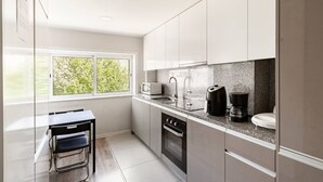 Uma cozinha moderna com armários brancos, micro-ondas, cafeteira e máquina de lavar louça.