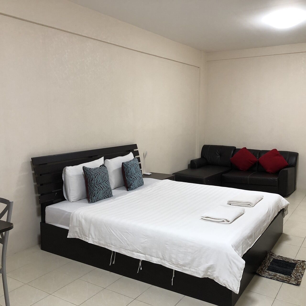 Quarto com uma cama grande, um sofá preto e uma mesa pequena.