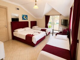Quarto de hotel com duas camas, televisão e varanda com cortinas.