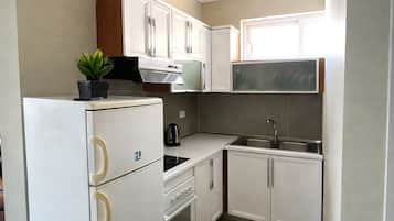 Um frigorífico, um forno, uma placa de cozinha, uma chaleira elétrica