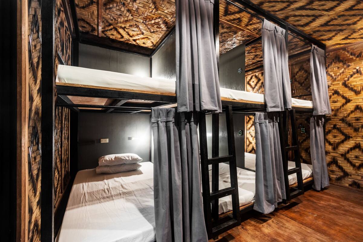 Quarto com beliches, paredes de madeira e cortinas.