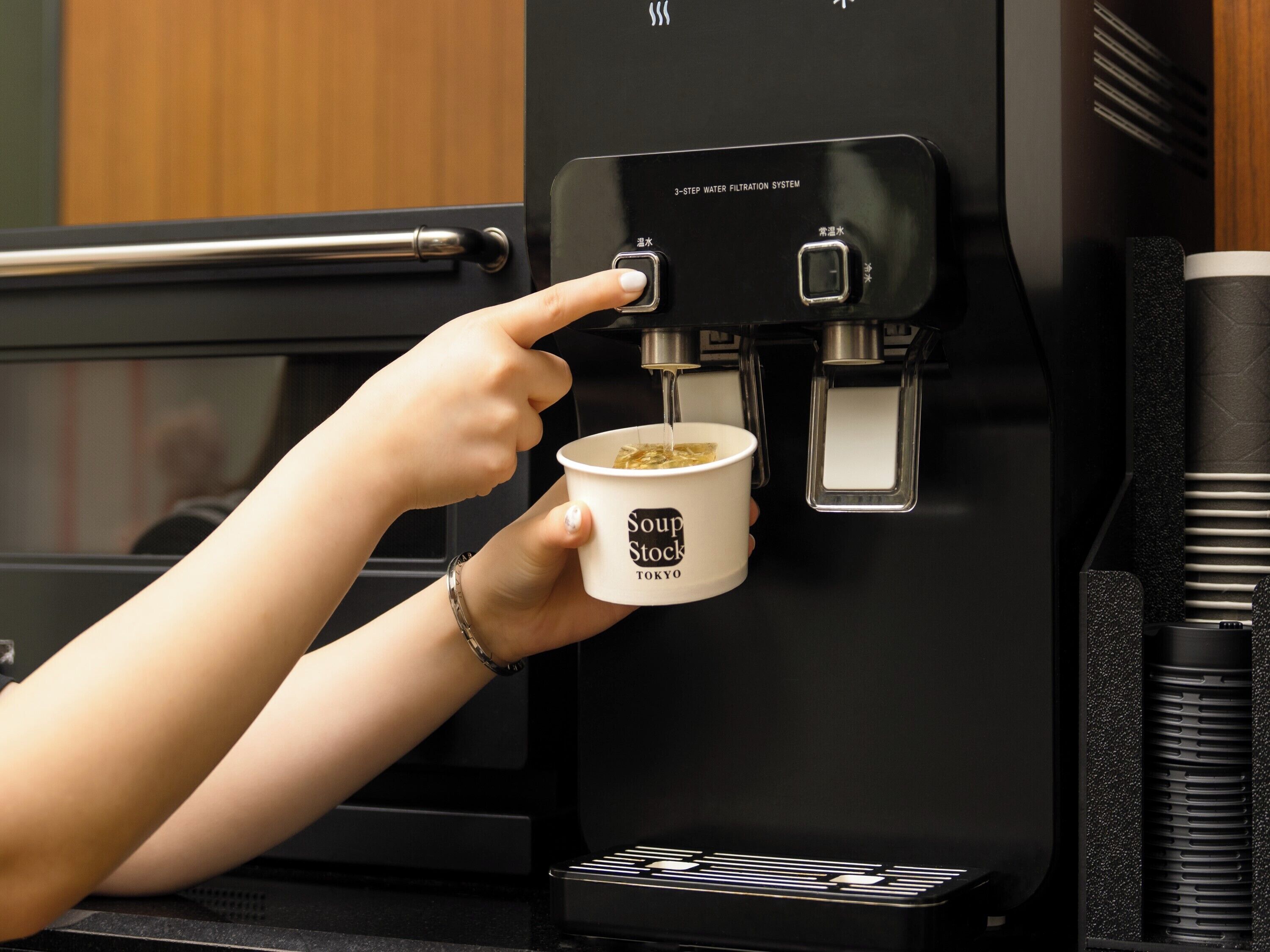 Alguém usando uma máquina de café para encher uma xícara.