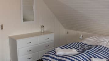 Quarto com cama, cômoda, espelho e abajur.