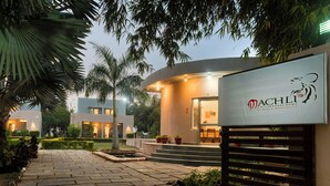 Uma entrada de hotel moderna com um letreiro, caminho pavimentado e paisagismo bem cuidado.