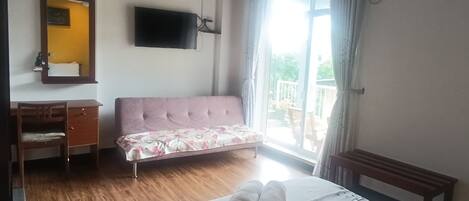 Quarto com cama, escrivaninha, cadeira, televisão e varanda.
