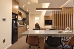 Cozinha moderna com ilha central, espaço para sentar e TV fixada na parede.