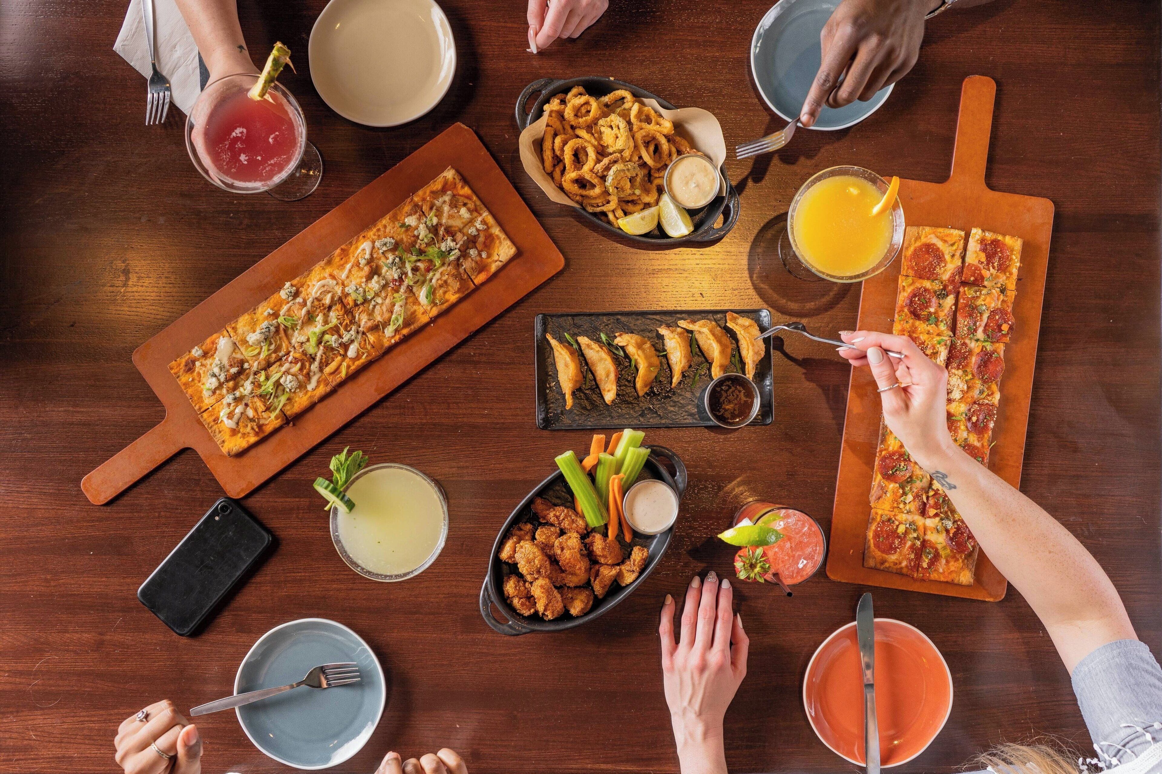 Uma mesa de jantar com diversos pratos, bebidas e utensílios.