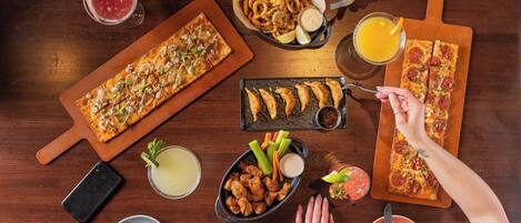 Uma mesa de jantar com diversos pratos, bebidas e utensílios.