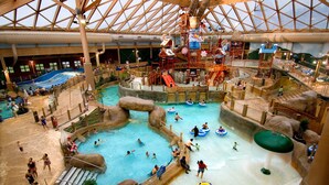 Parque aquático em ambiente fechado com várias piscinas, toboáguas e áreas de recreação aquática.