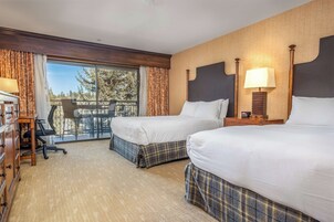 Quarto de hotel com duas camas, uma mesa e uma cadeira.