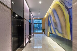 Um interior moderno com parede de vidro, piso de mármore e um grande mural abstrato.