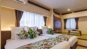 Quarto de hotel com duas camas, uma mesa de trabalho e aparelho de ar condicionado.