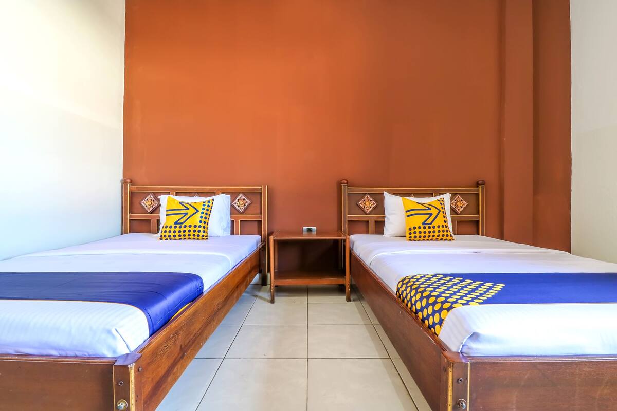 Quarto com duas camas de madeira, cada uma com colcha e almofadas azuis.