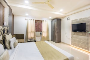 Quarto de hotel com cama, televisão, guarda-roupa e ar condicionado.