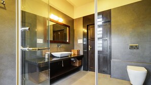 Uma casa de banho moderna com cabine de duche em vidro, lavatório branco e sanita.