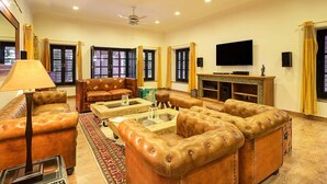 Uma sala de estar ampla com sofás de couro, uma mesa de centro, uma televisão e uma lareira.