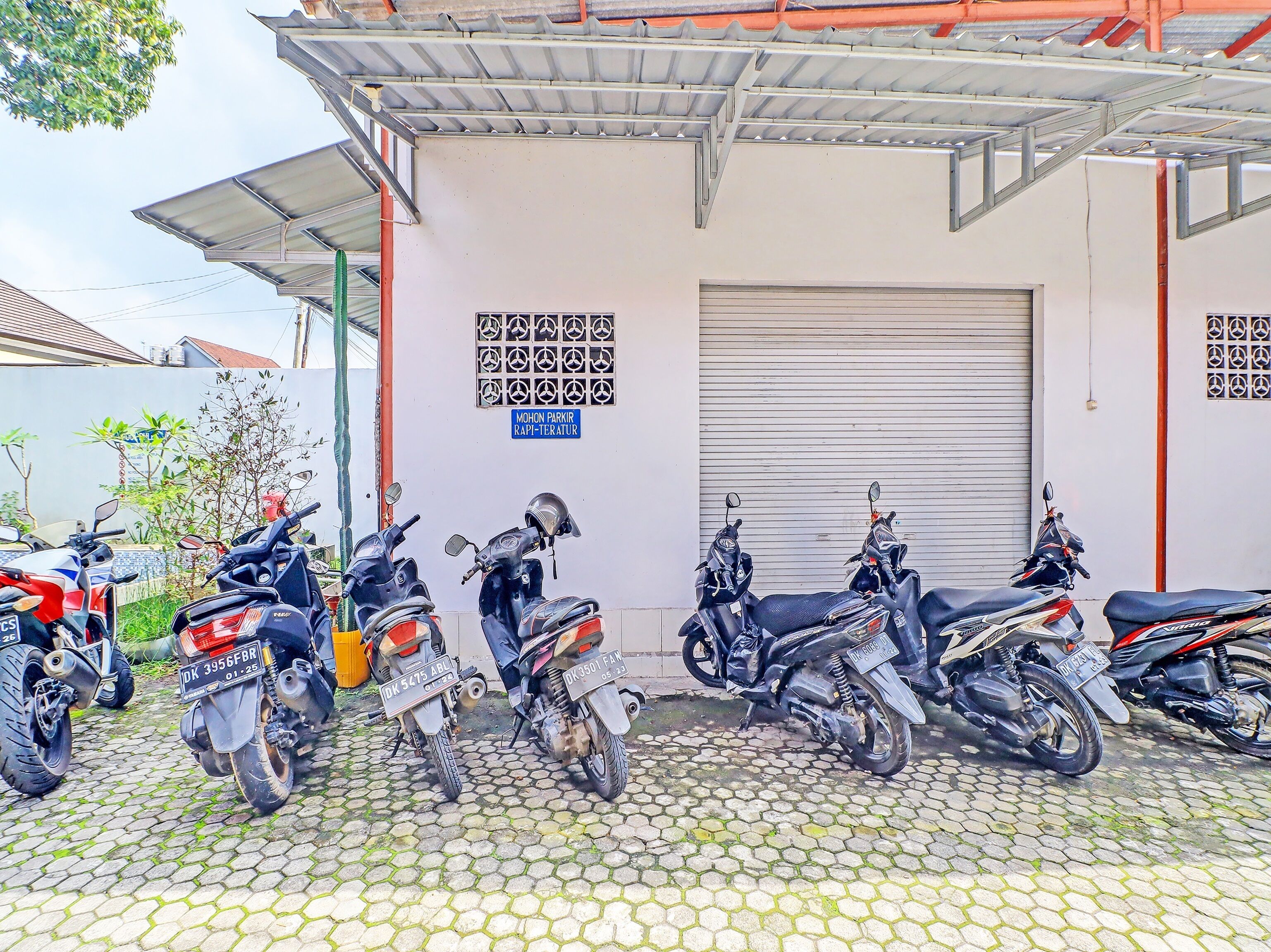 Várias motocicletas estacionadas em frente a um edifício com porta de garagem.