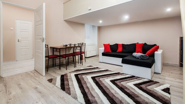 Uma sala de estar moderna com um sofá, uma mesa de jantar com cadeiras e um tapete estampado.