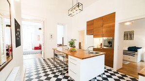 Uma cozinha moderna com uma ilha central, armários de madeira e piso quadriculado preto e branco.