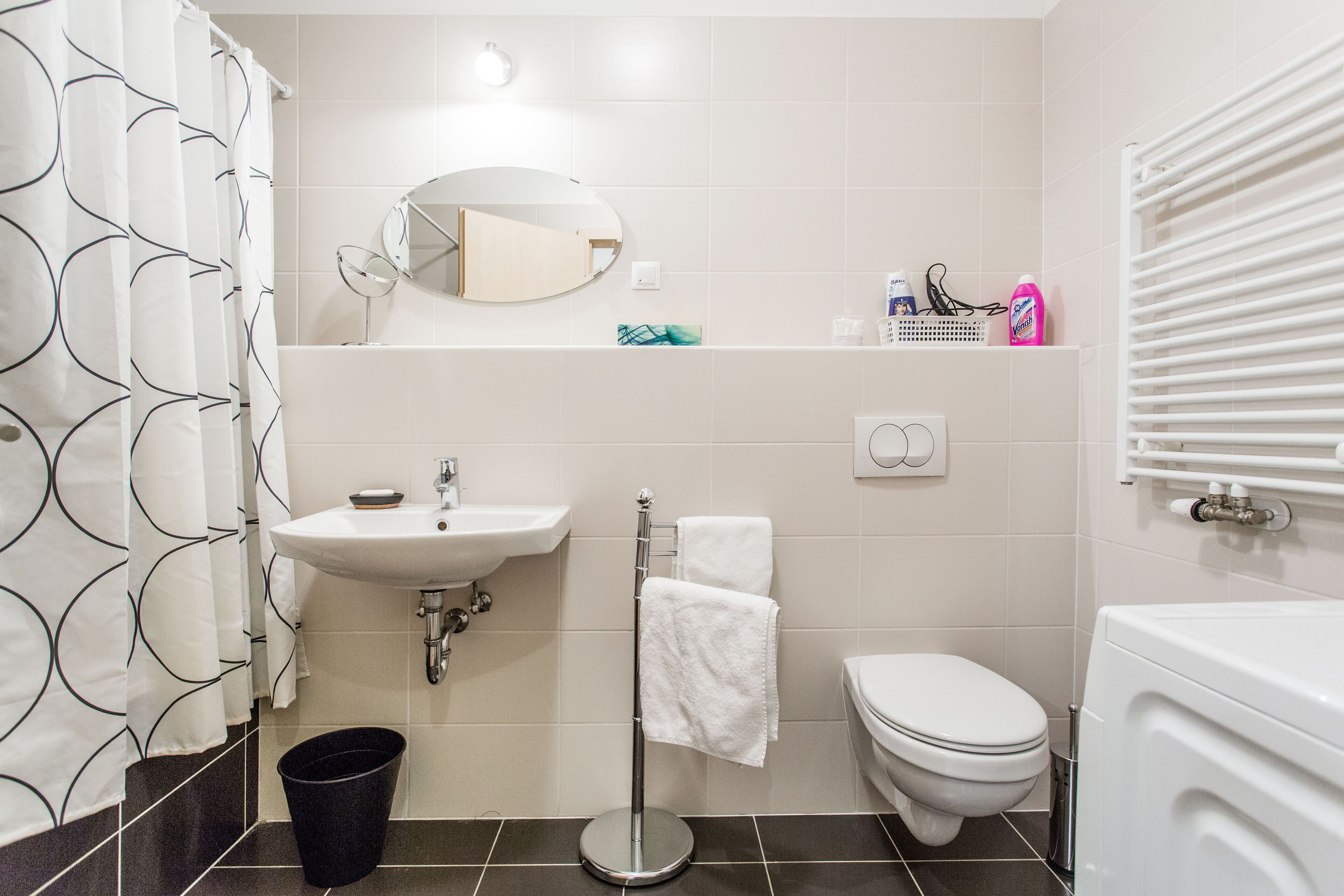 Uma casa de banho moderna com lavatório branco, sanita e zona de duche.