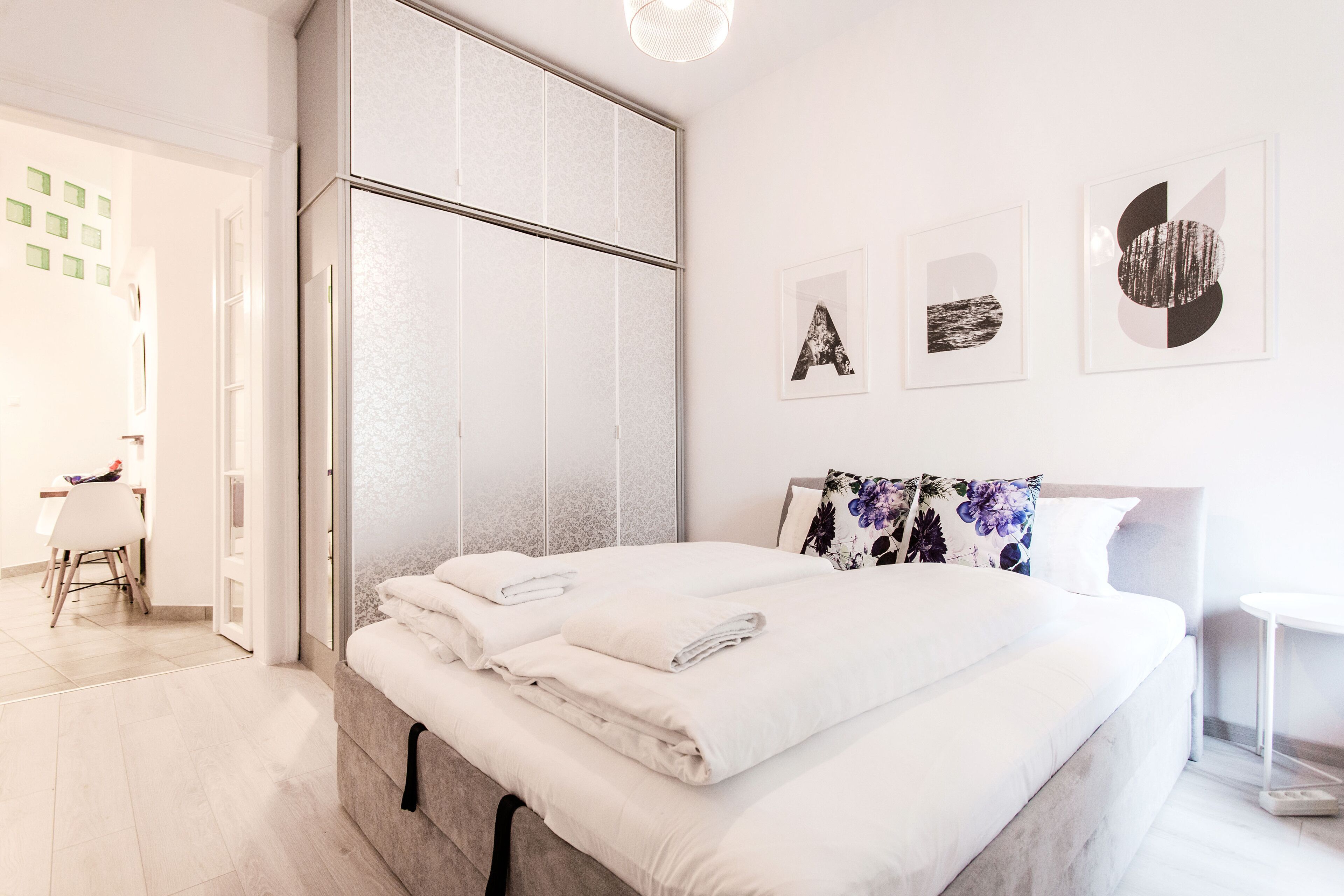 Quarto moderno com uma cama grande, um guarda-roupa e obras de arte na parede.