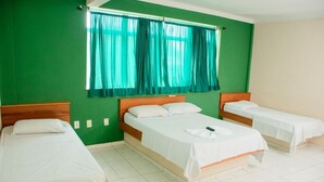 Quarto com três camas, paredes verdes e janela com cortinas.
