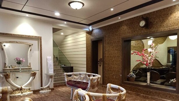 Um hall com cadeiras ricamente decoradas, um espelho grande e uma escadaria.