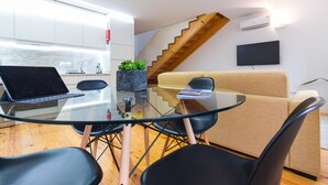 Uma cozinha moderna com armários brancos, uma mesa de jantar de vidro e um laptop.
