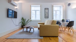 Uma sala de estar moderna com sofá, mesa de centro, TV e área de jantar com cadeiras e mesa.