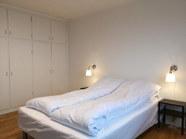 Quarto com cama, duas mesas de cabeceira e guarda-roupa.