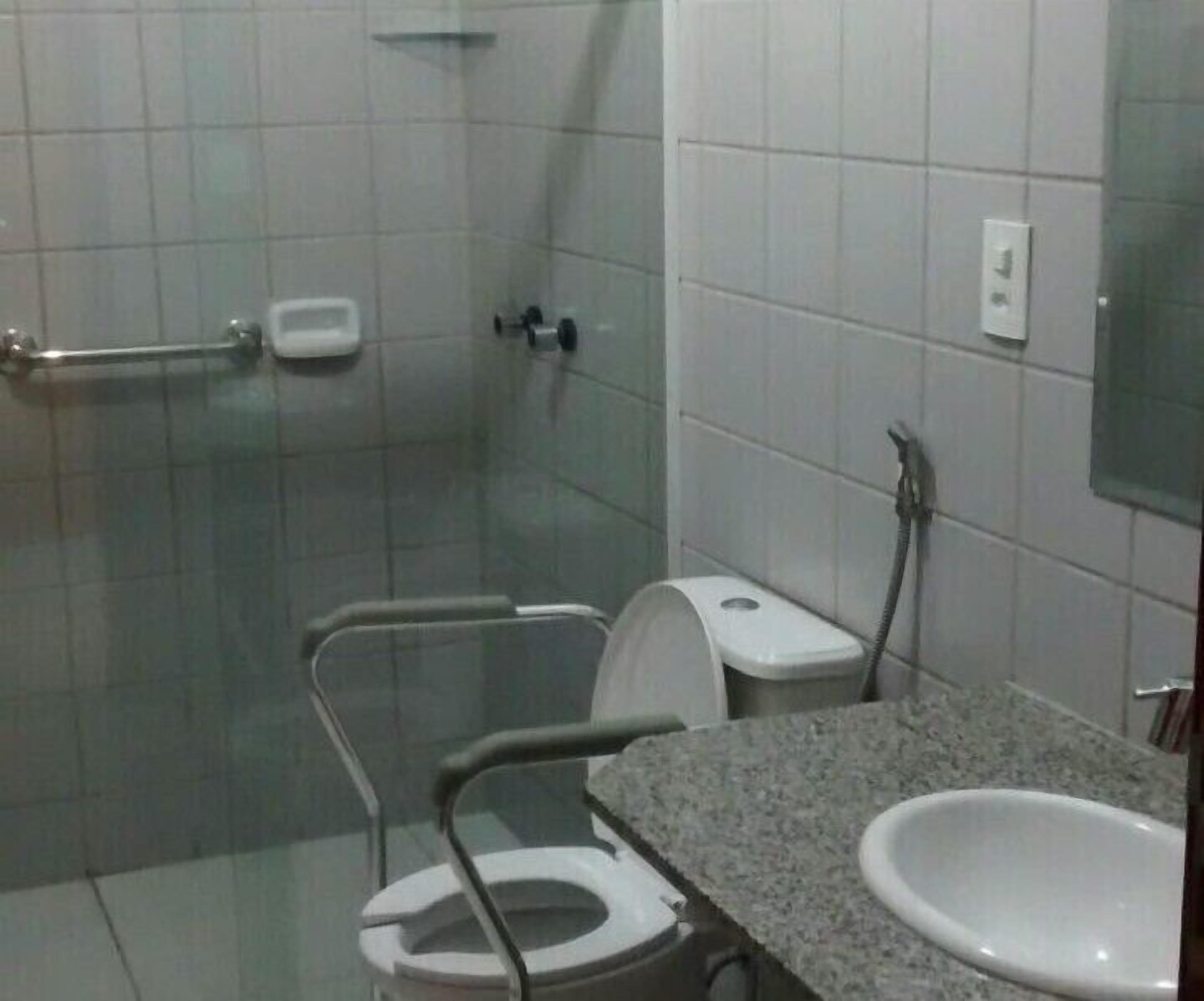 Uma casa de banho com chuveiro, sanita e lavatório.
