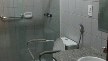 Uma casa de banho com chuveiro, sanita e lavatório.