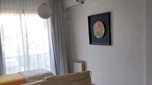 Um quarto com um sofá bege, uma obra de arte emoldurada na parede e um radiador.