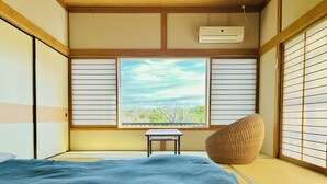 Um quarto japonês tradicional com tatames, um futon, uma mesa baixa e uma cadeira de fibra natural.