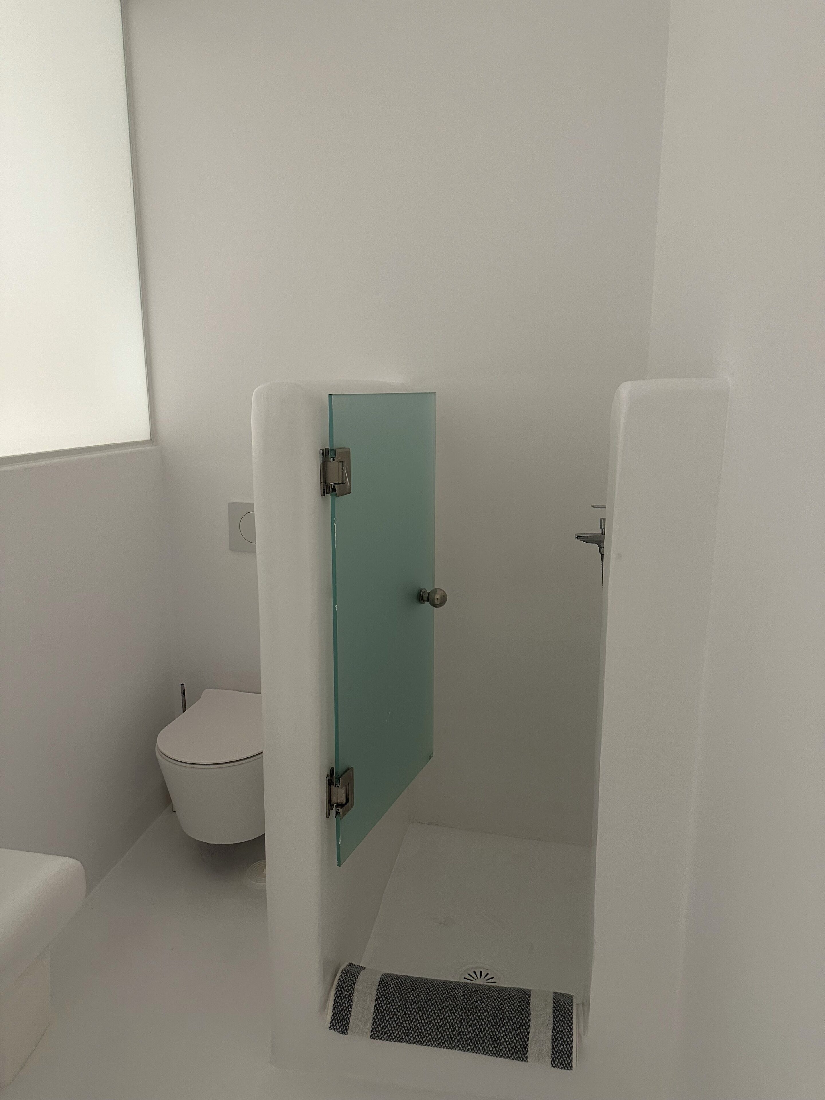 Casa de banho pequena e privada, com sanita, cabine de duche e uma porta.