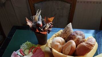 Uma mesa posta para o café da manhã, com pão, presunto, queijo e frutas.