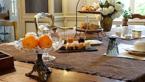 Uma mesa de café da manhã com doces, laranjas e um vaso de flores.