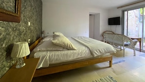 Quarto com uma cama, uma cadeira, uma TV e uma janela.